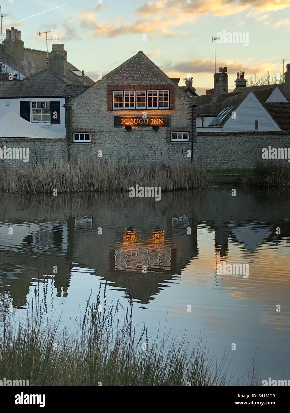 The Plough Inn pub and other old stone buildings with reflections in a ...