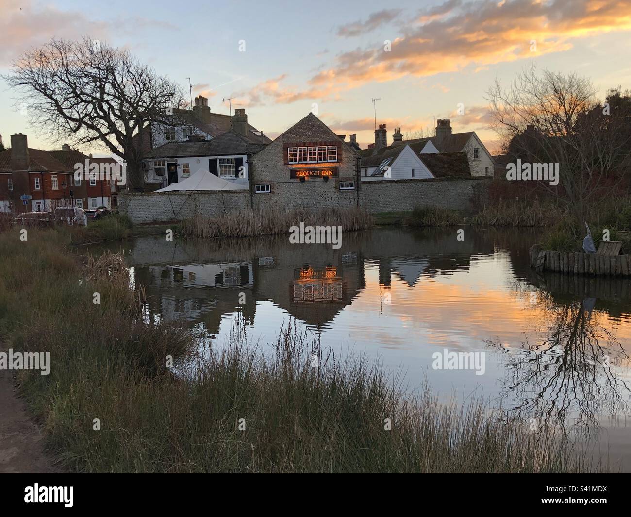 The Plough Inn pub and other old stone buildings with reflections in a ...