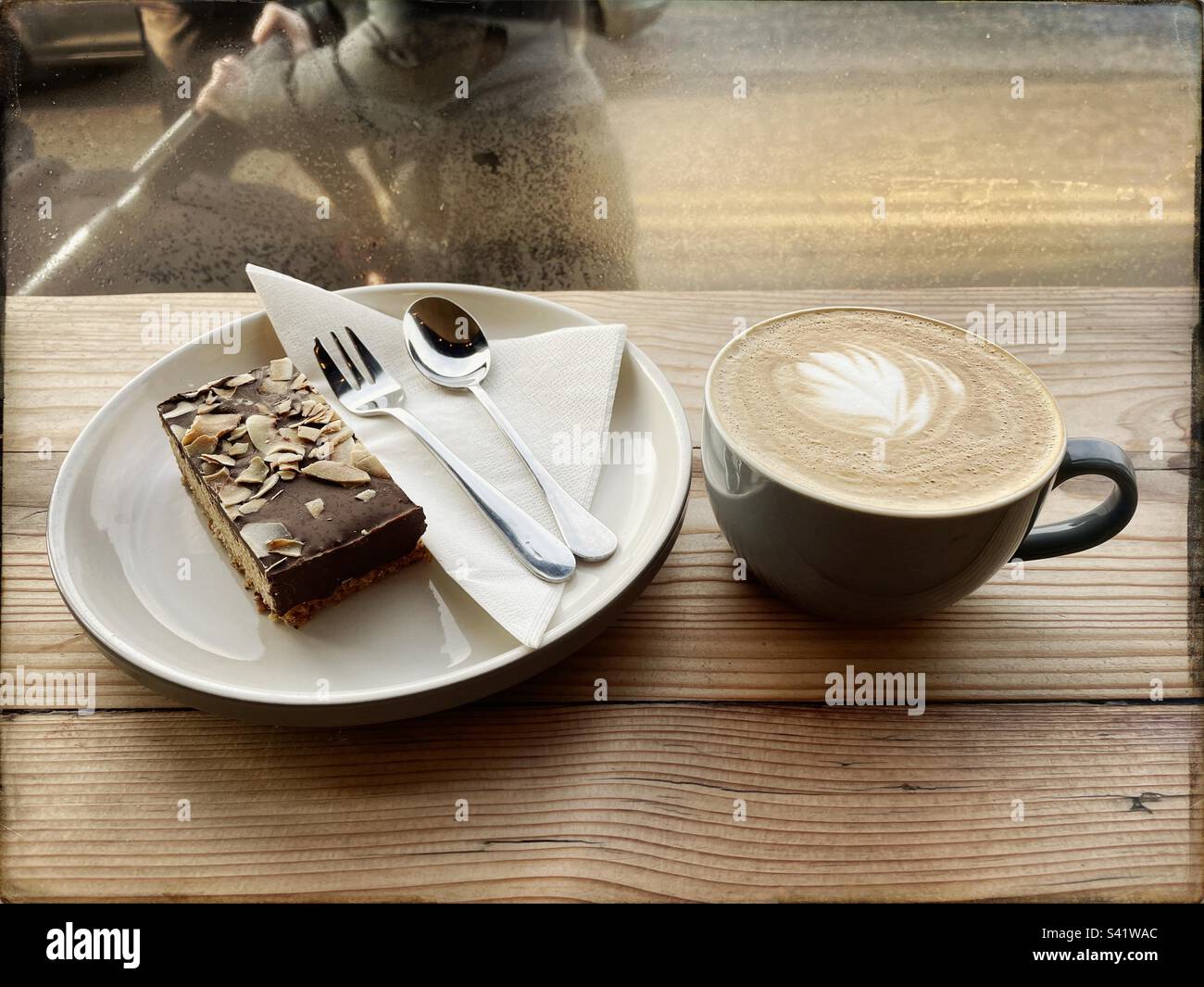 Watching the world go by in a cafe with a flat white coffee and a piece ...