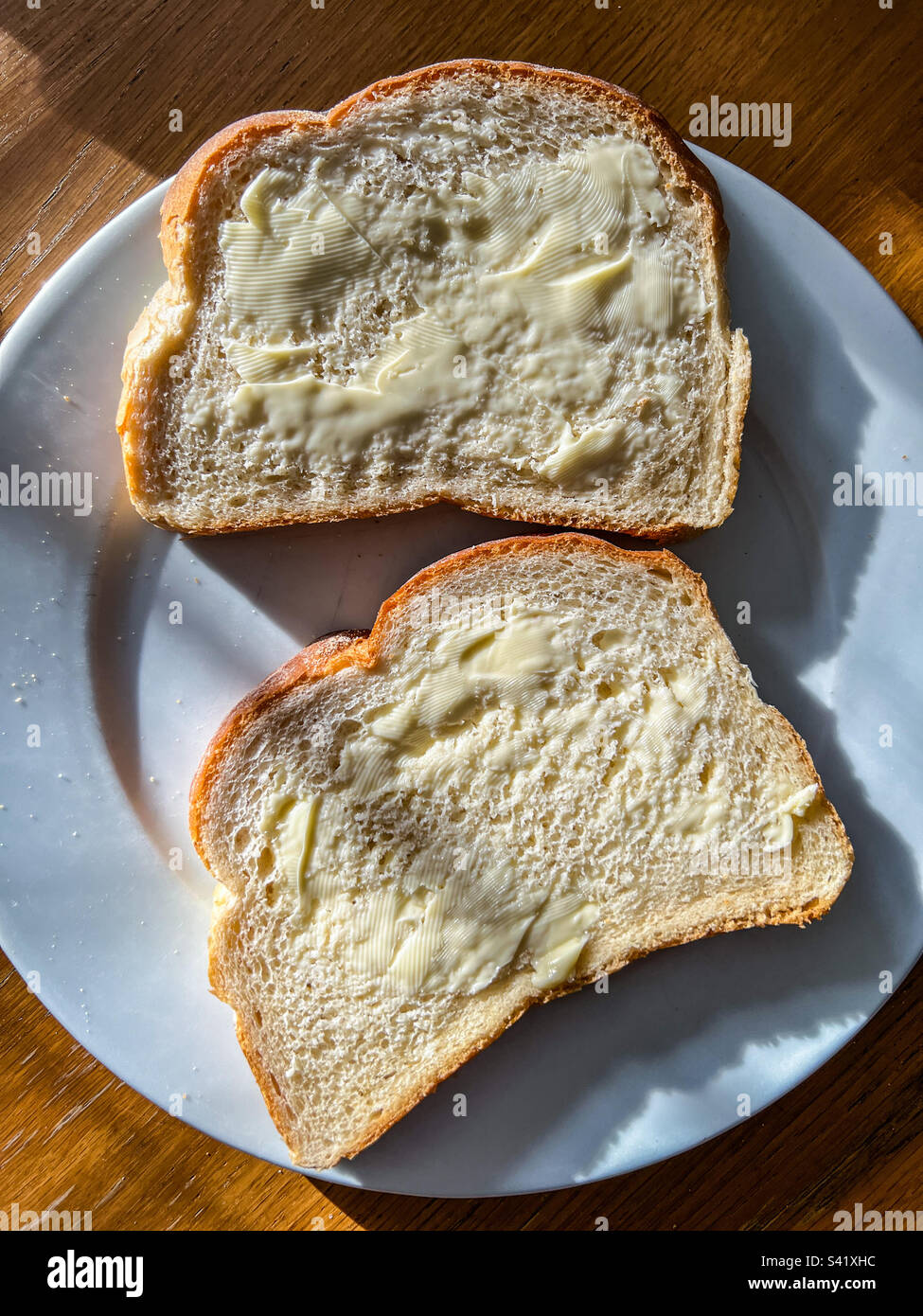 Two slices of buttered white sliced bread on white plate Stock Photo ...
