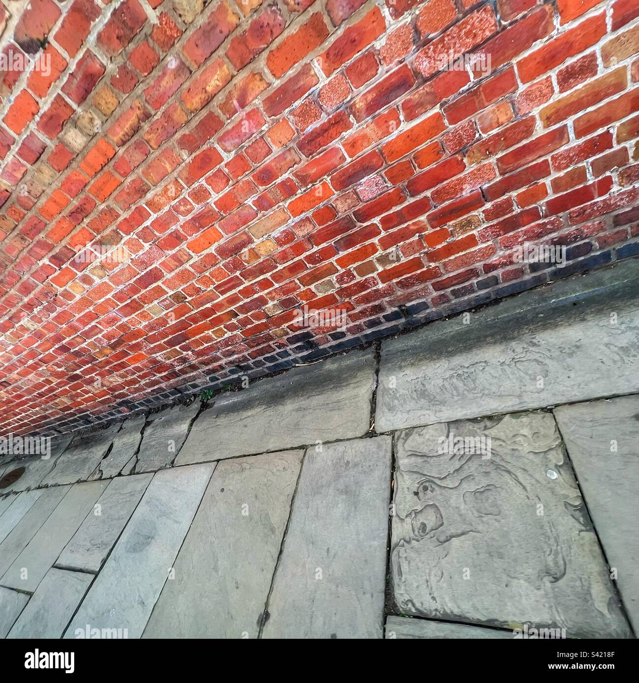 Contrast of red brickwork against grey paving stones Stock Photo - Alamy