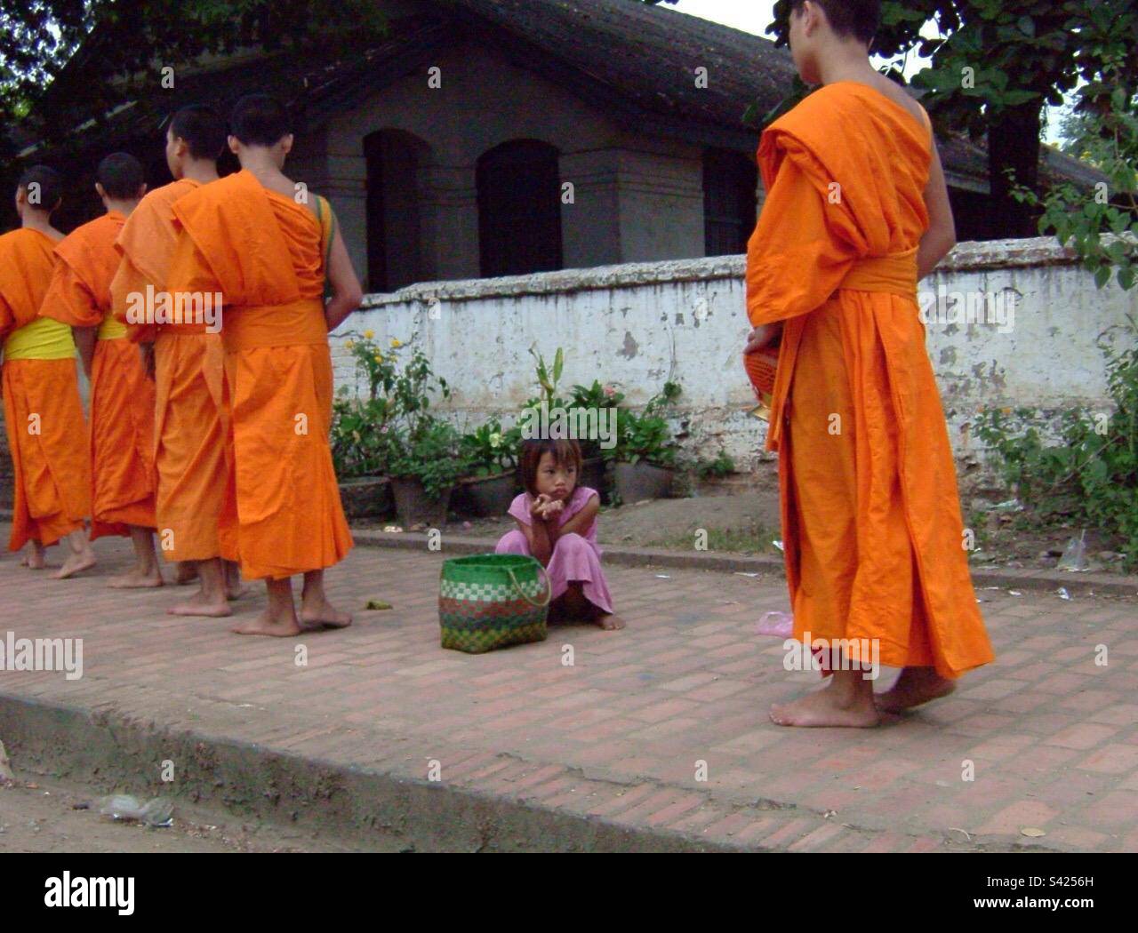 Luang Prabang , young street urchin begging as monks pass by Stock ...