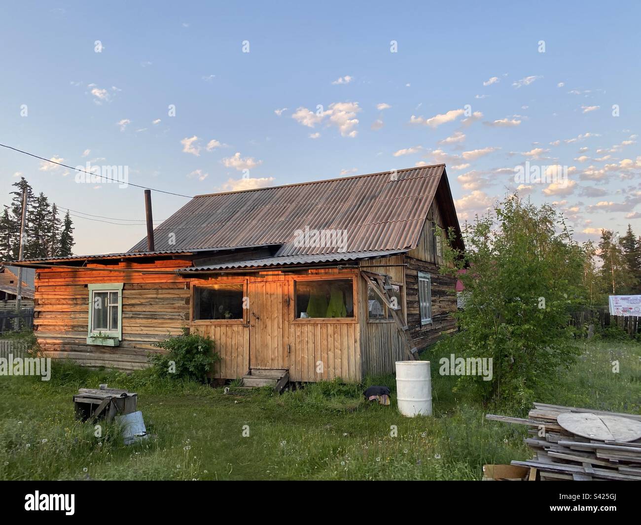 Wooden cottage in the garden in summer at sunset in Yakutia in Siberia ...