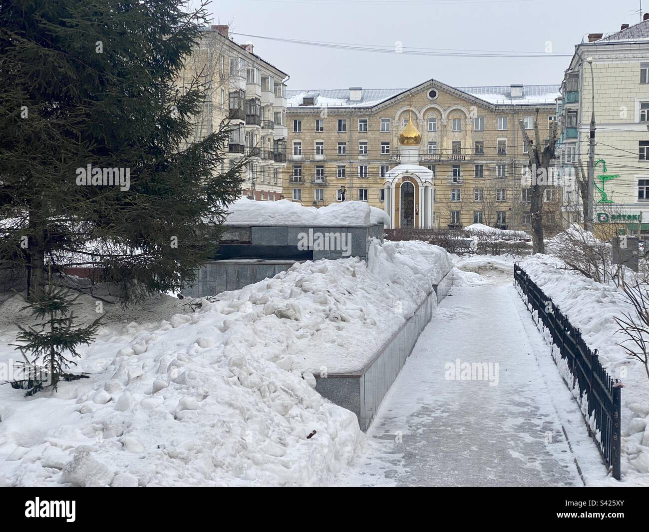 A small temple with a golden dome stands in old apartment buildings in ...