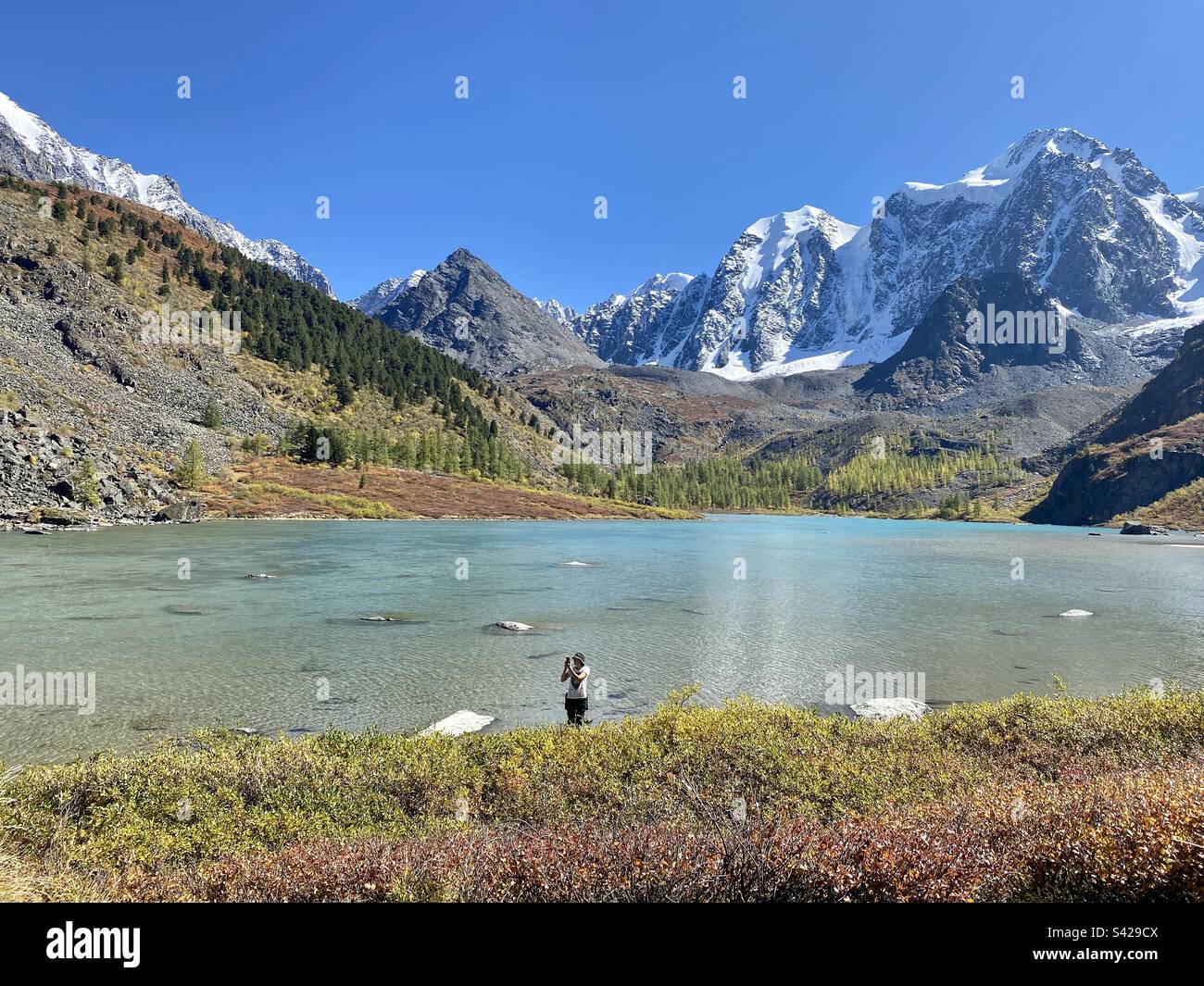 A tourist girl on the shore of the Alpine lake Shavlinskoye near the ...