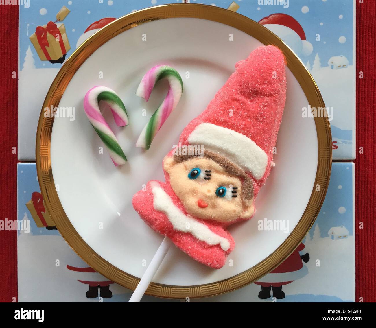 Christmas Elf lollipop, appearing to look at a couple of candy canes on ...
