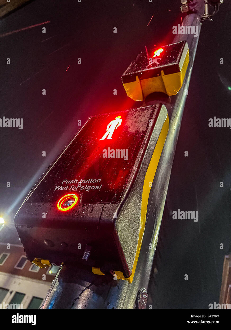 Red man light at pedestrian crossing at night in city centre in rain ...