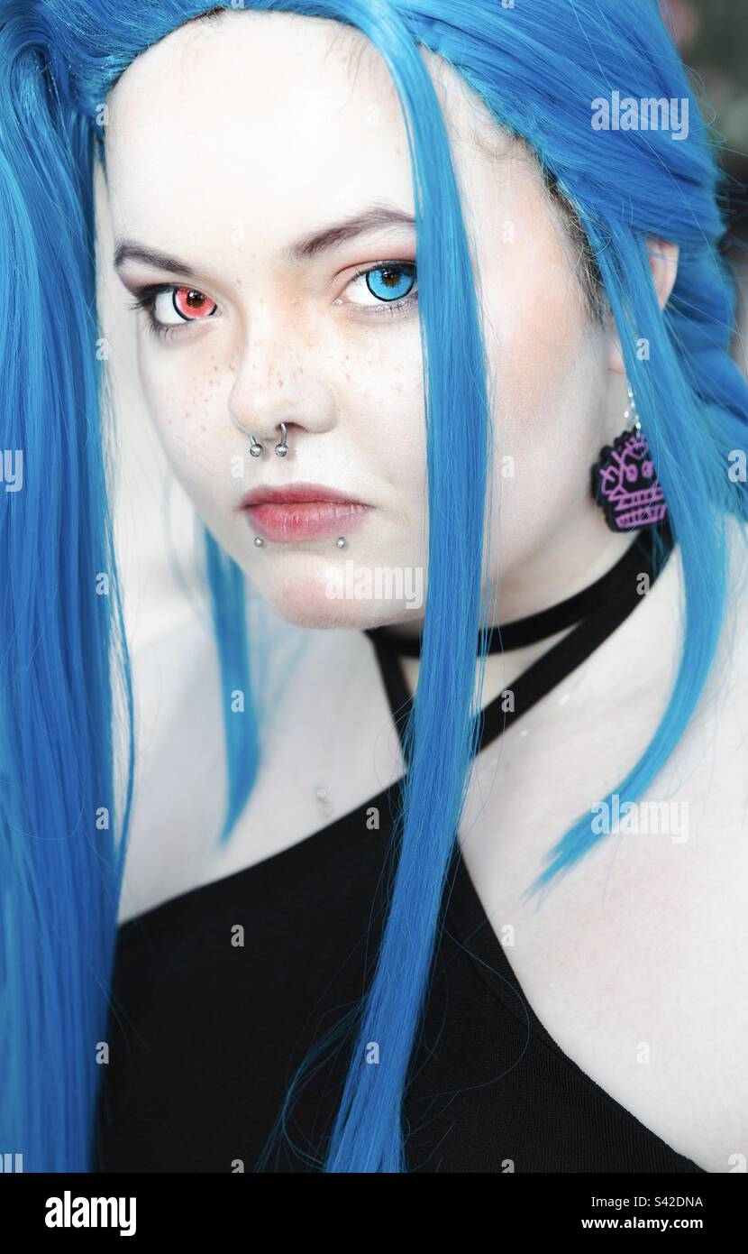 Teen rebel girl with blue hair and face piercings wearing colourful ...