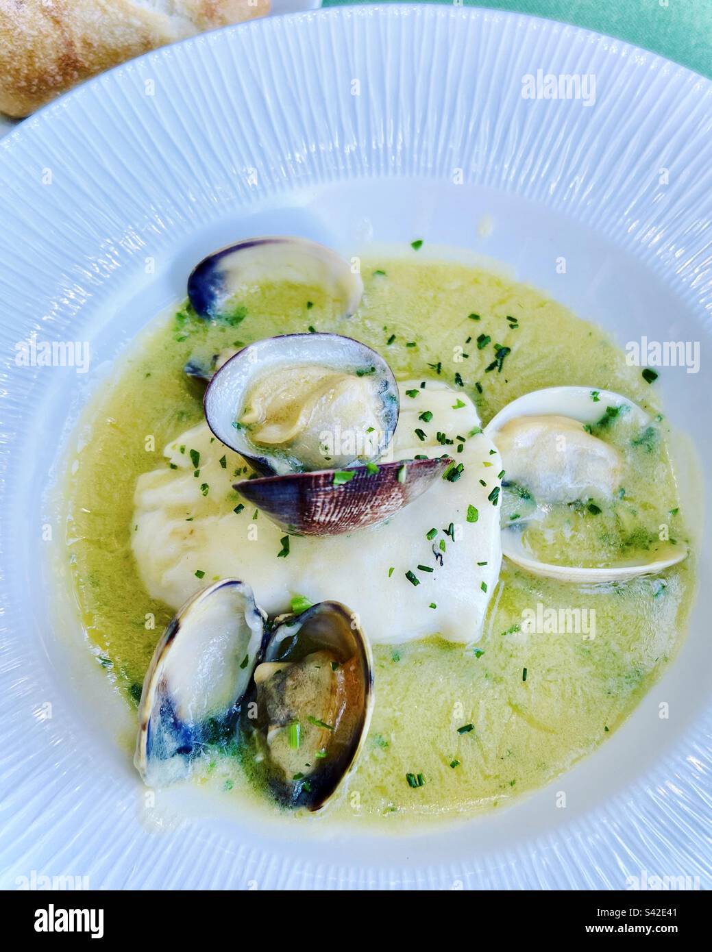 Juicy, tender clams atop fresh, flaky hake fish in a saffron infused ...