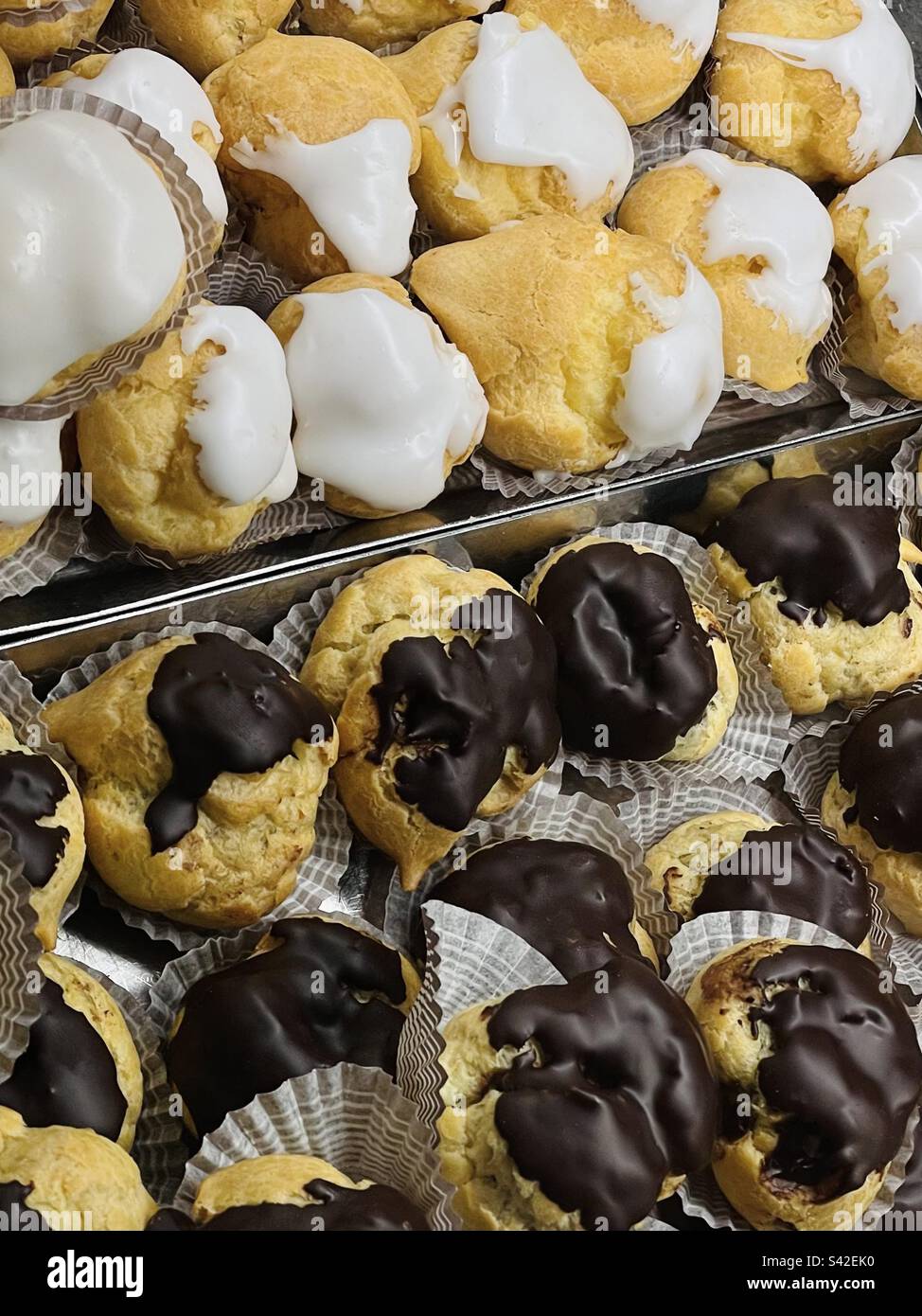 Cream puff and chocolate profiteroles on display in bakery shop Stock ...