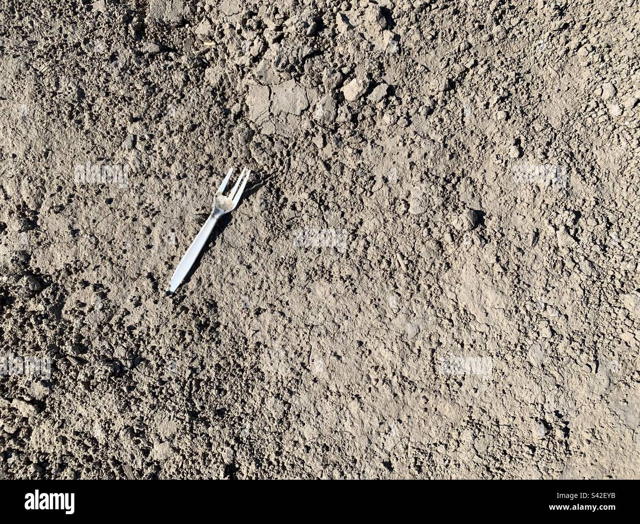 Dried mud and plastic fork, environmental pollution Stock Photo - Alamy