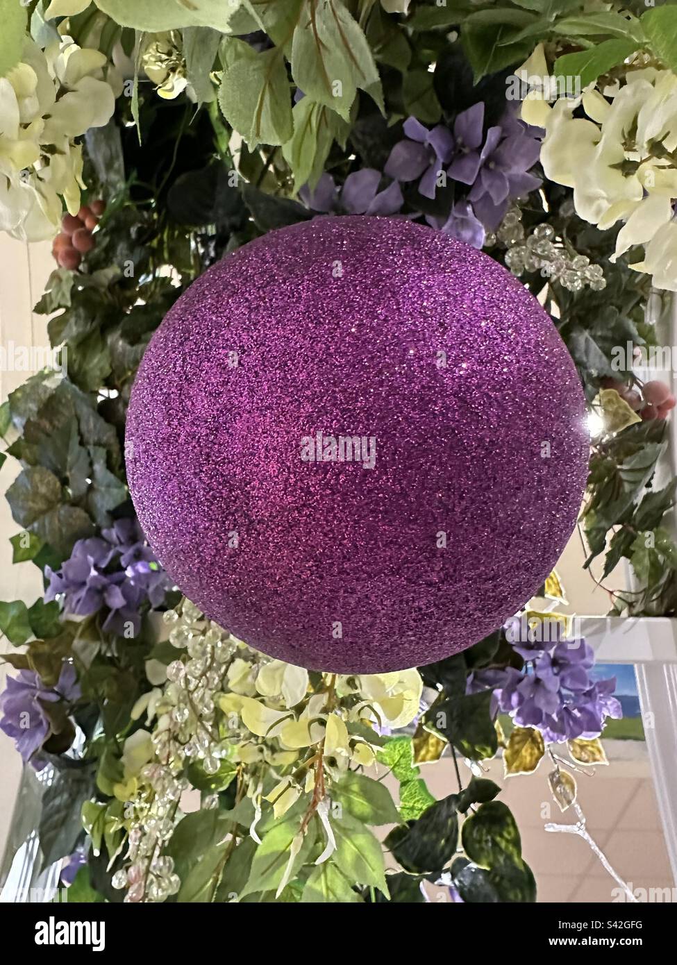 Sparkly, purple ornament, hanging from fake vines with fake flowers ...