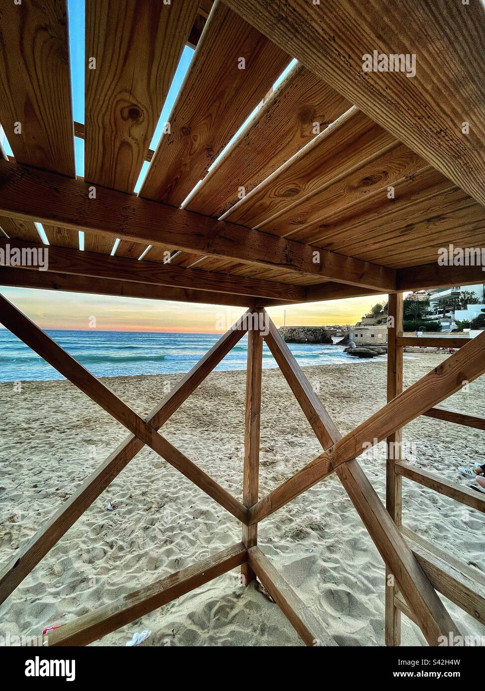 Through the wooden lifeguard lookout the sun sets Stock Photo - Alamy