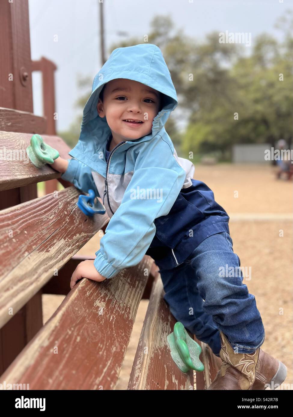 3 year old little boy playing on playground equipment at a park on an ...