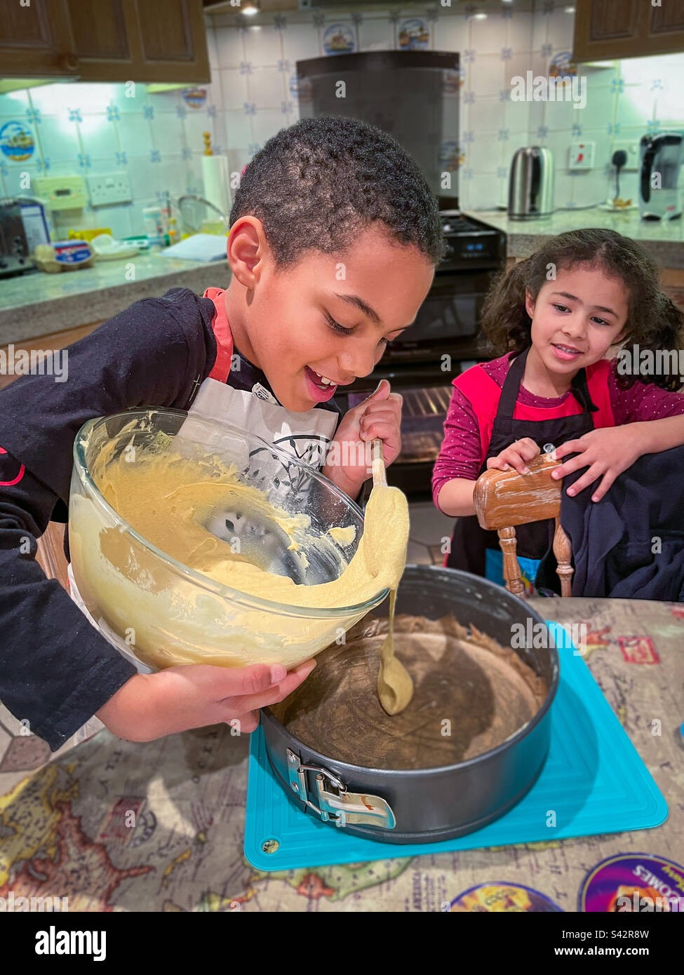 Young boy and girl enjoying making a cake at home Stock Photo - Alamy