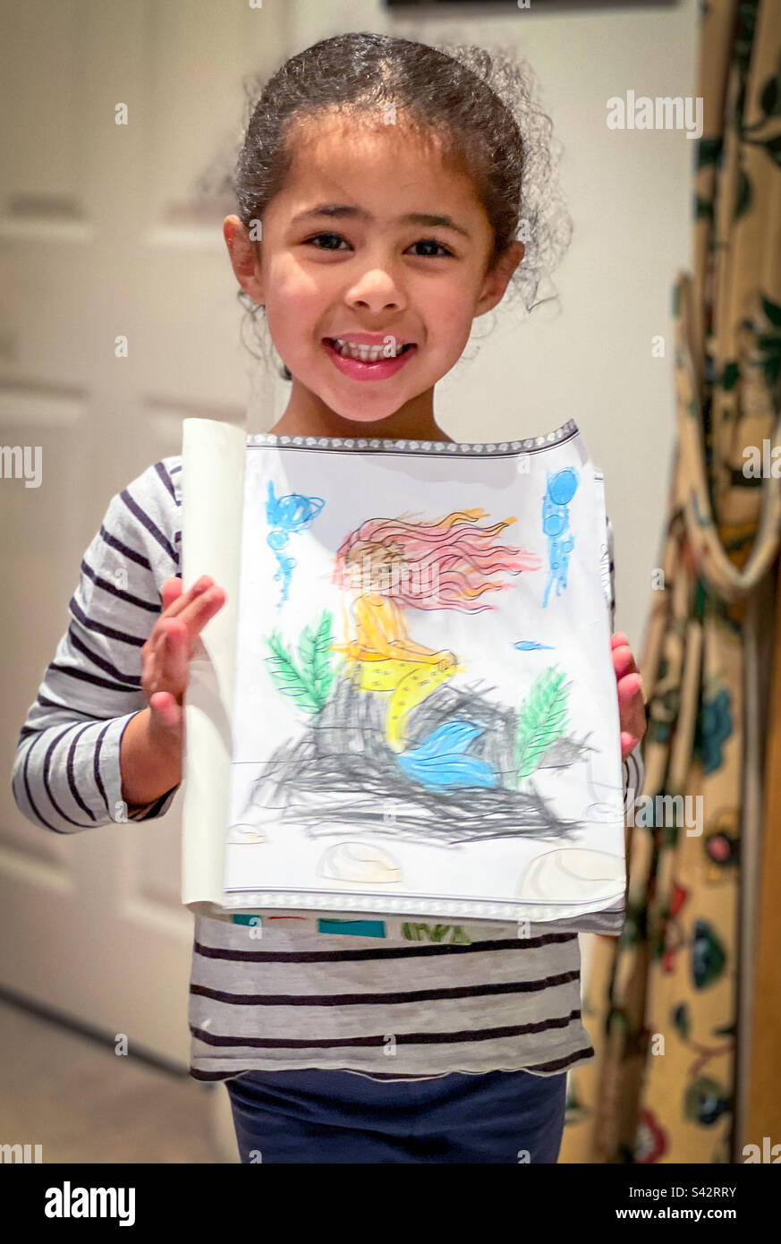 Young girl aged 4 proudly showing off her drawing of a mermaid Stock ...