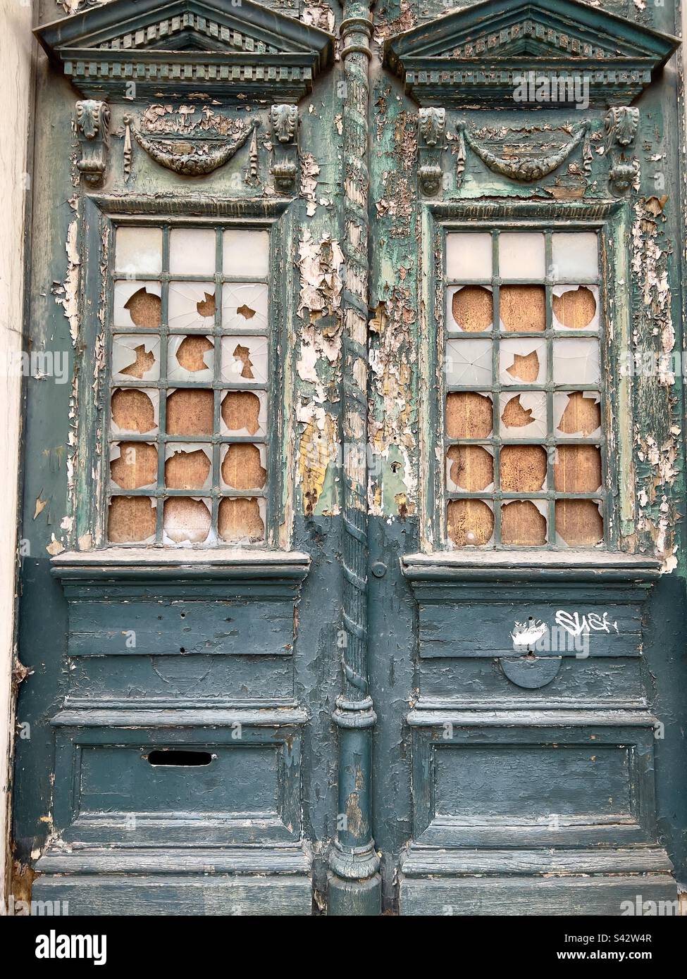 Old traditional weathered green door detail with broken glass panels ...