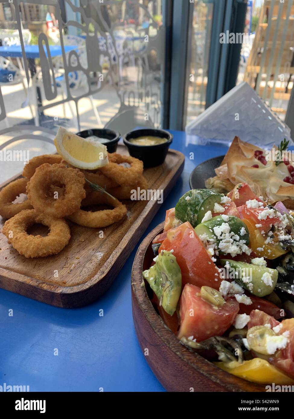 Calamari rings and a Greek salad on a blue table in a restaurant Stock ...
