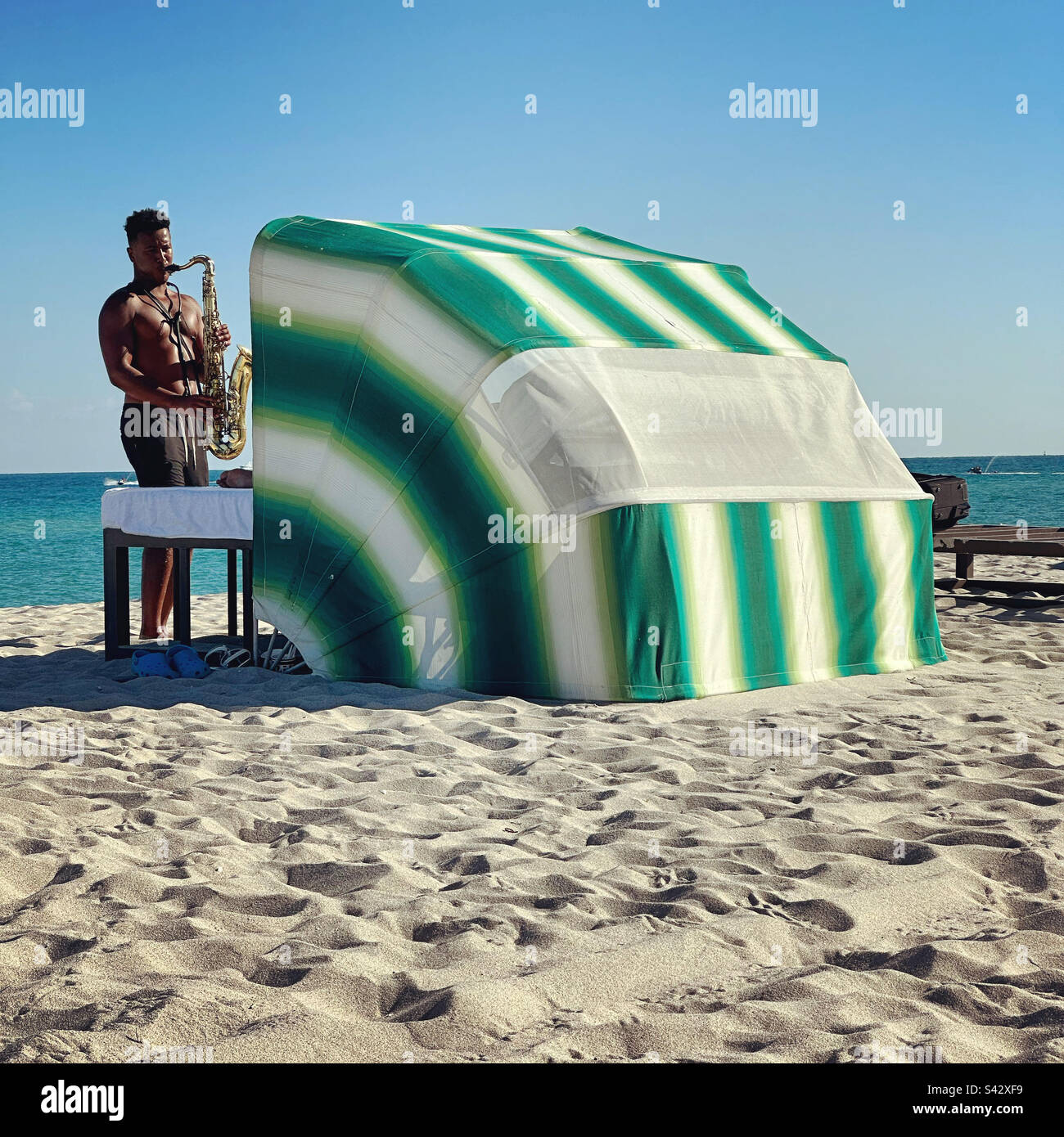 January, 2023, Busker playing a saxophone in front of a beach cabana ...
