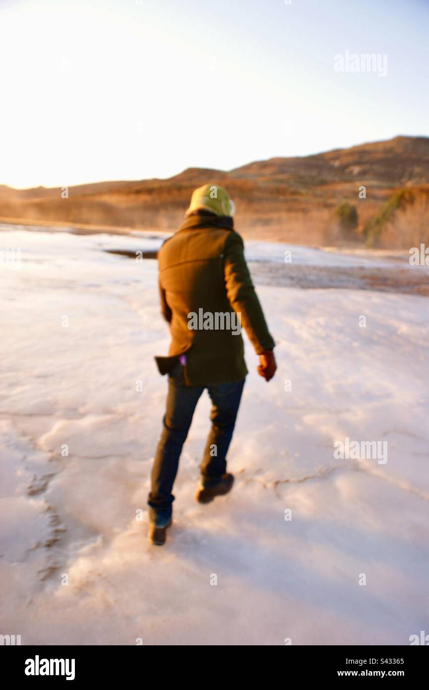 Man walks carefully over the slippery ice in Iceland winter at sunset ...
