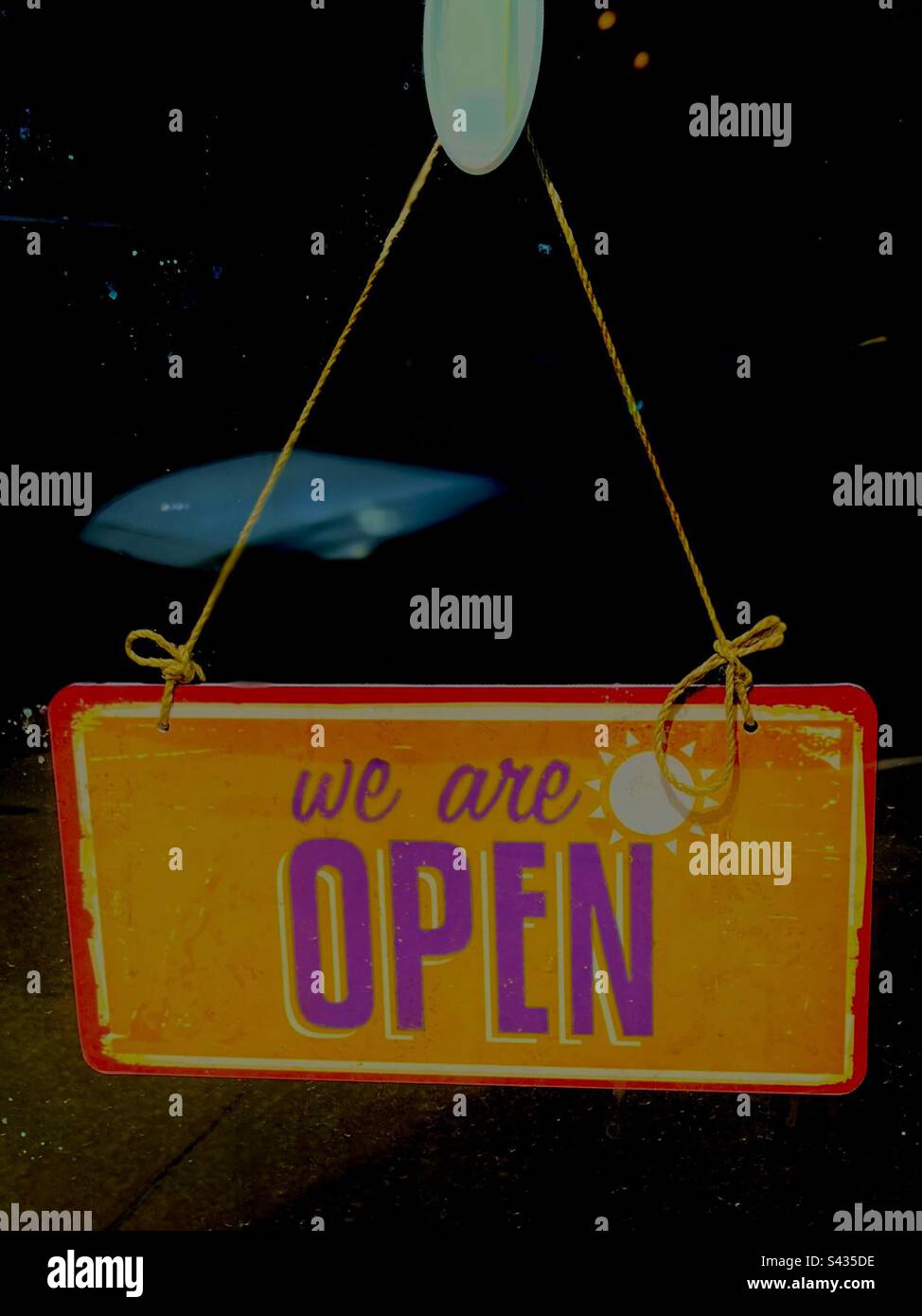 Orange and pink hanging sign, says OPEN against black background ...
