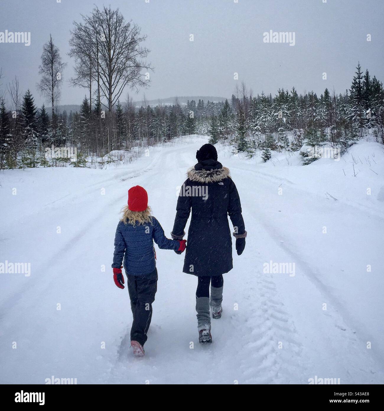 A mother and daughter walking a remote country road through a frozen ...