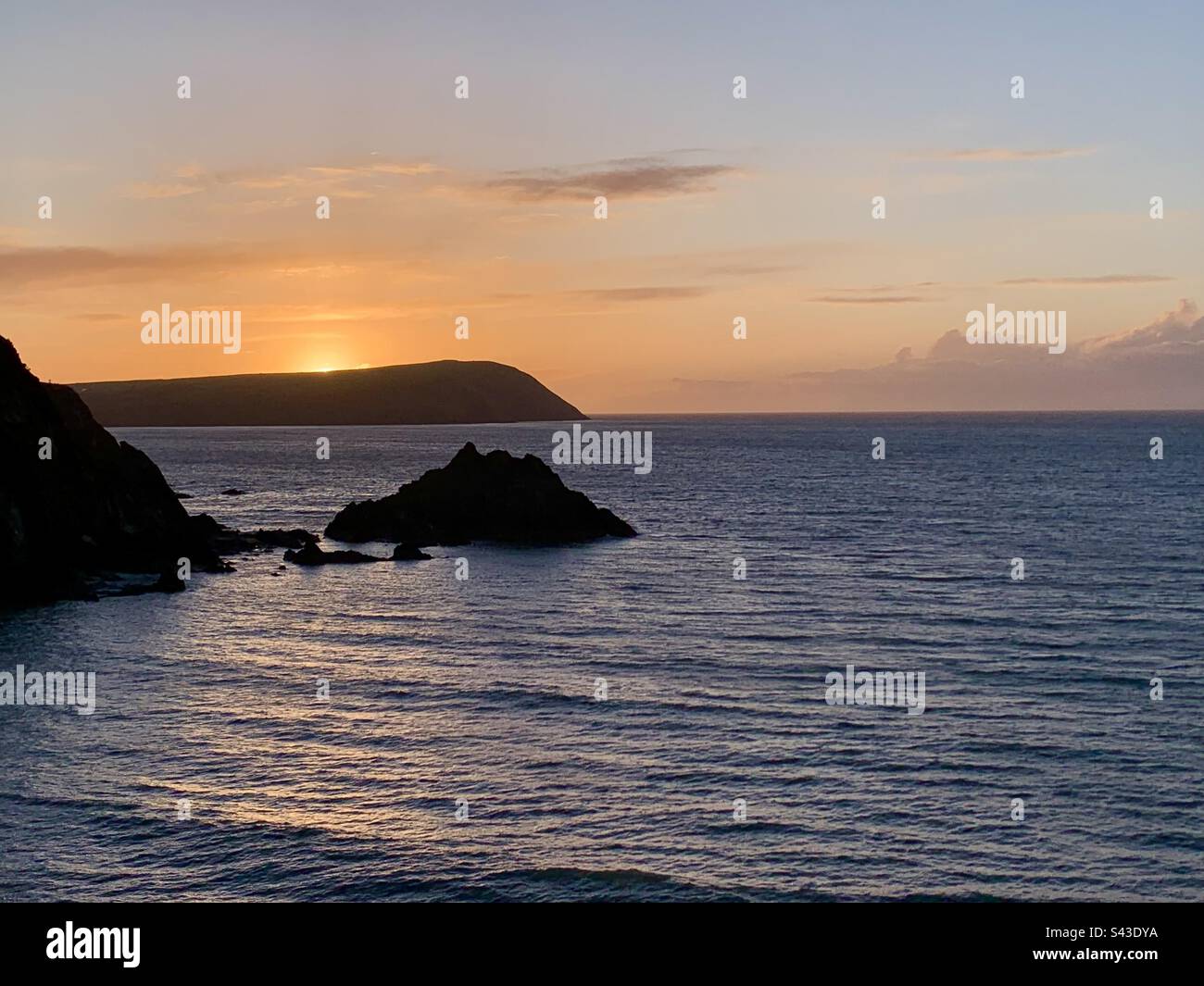 Orange sunset sky dipping down behind Dinas headland over sea Stock ...