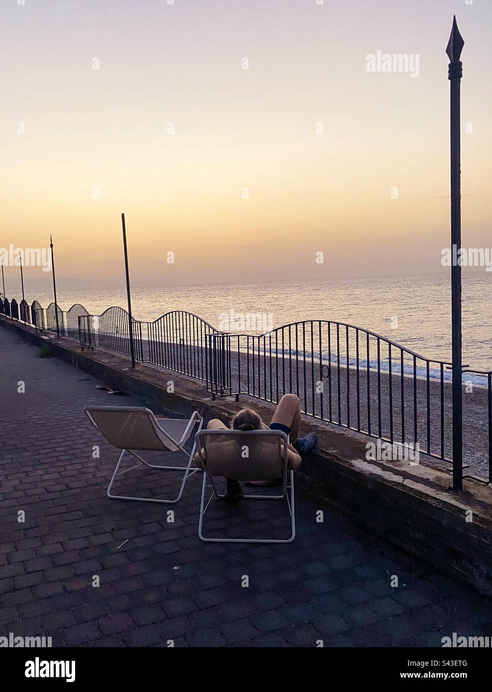 Man lounging in beach chair as sun is going down Stock Photo - Alamy