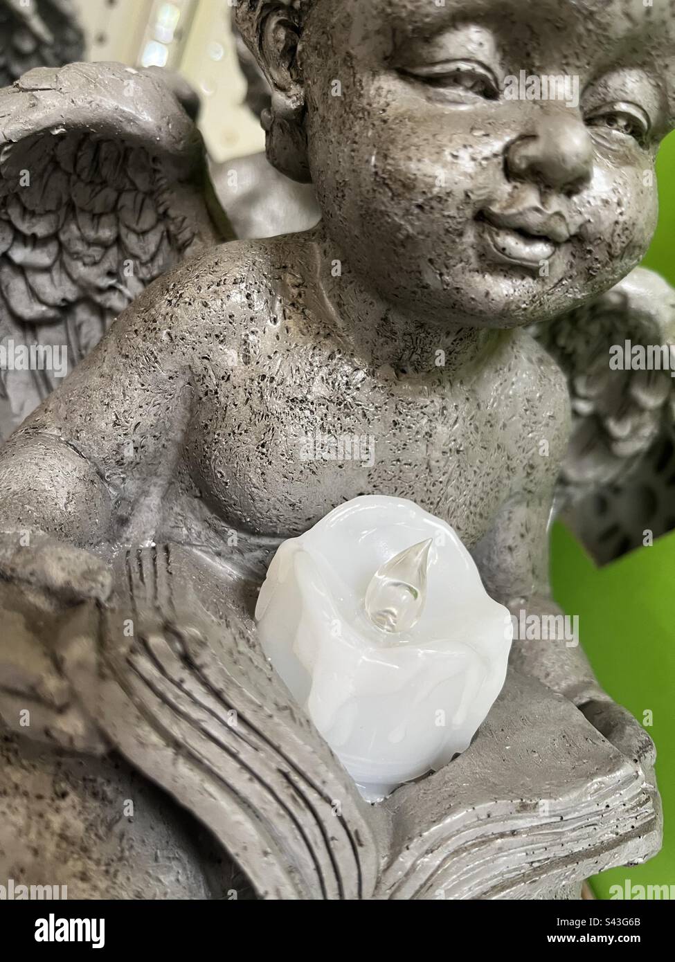 Baby Angel sculpture holding book with white candle Stock Photo - Alamy