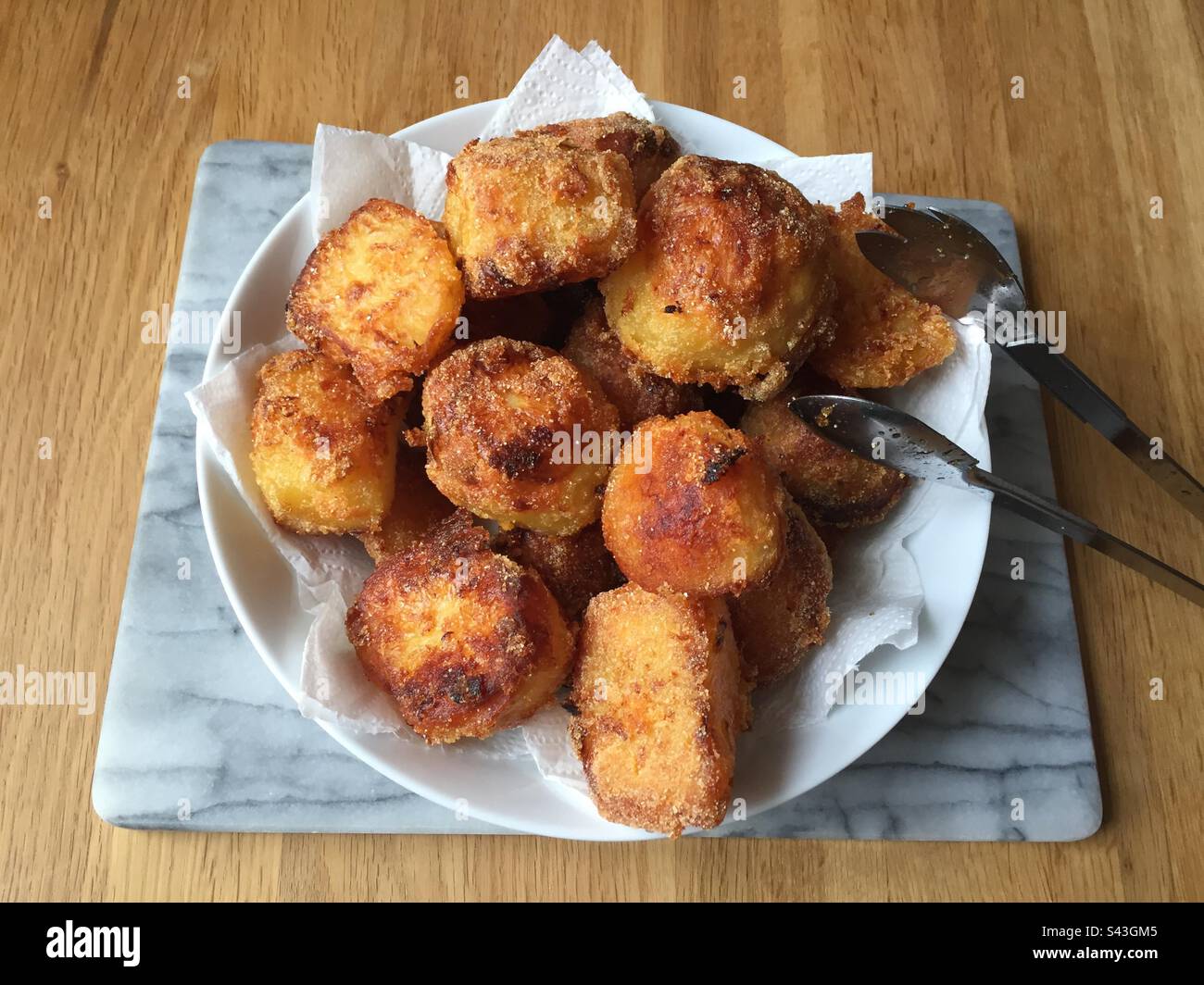 Roast potatoes in a serving dish. Golden roast potatoes, crunchy on the ...