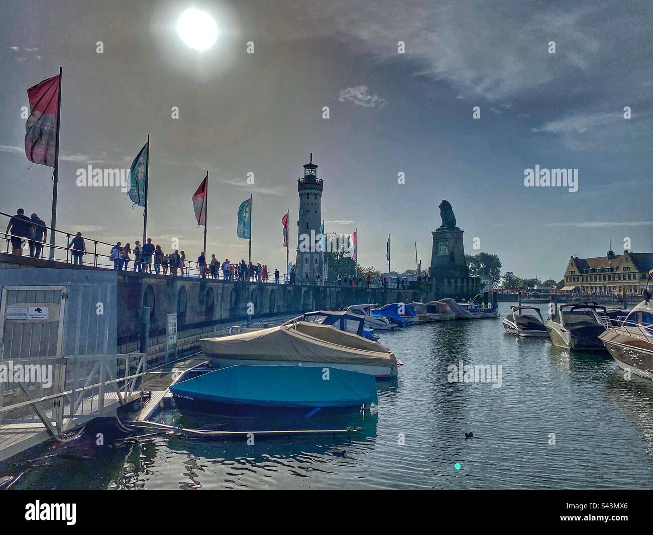 Silhouettes of walking people in Lindau harbor on lake Bodensee with ...