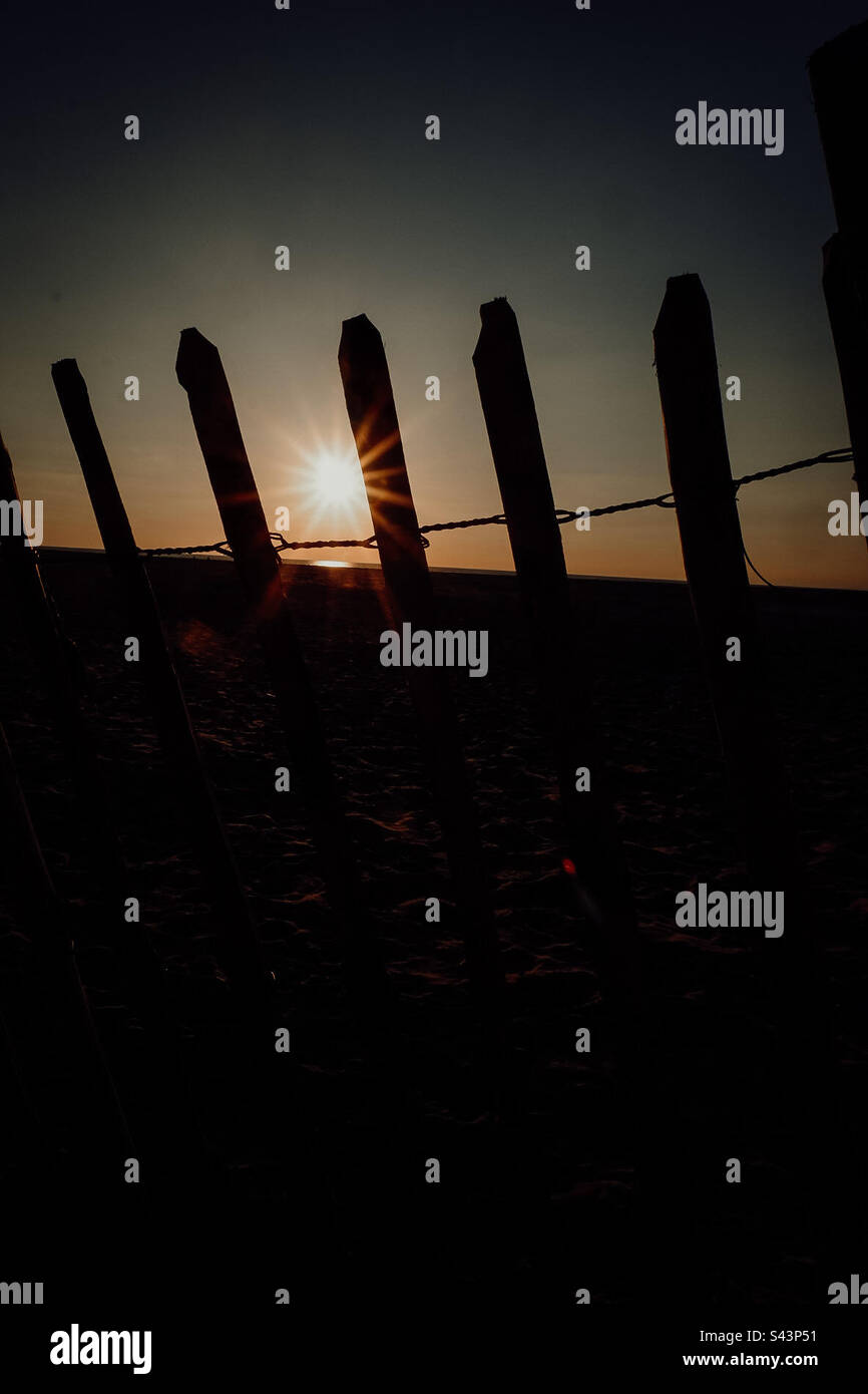 Sunset through the fence line Stock Photo - Alamy