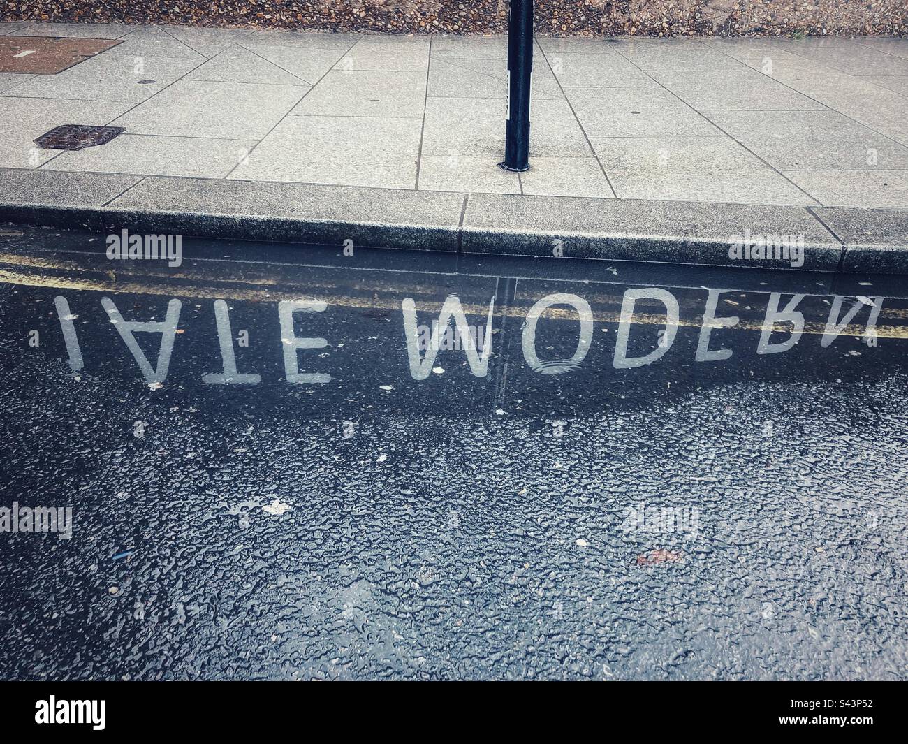 Tate modern lettering mirrored Reflection in a puddle Stock Photo - Alamy