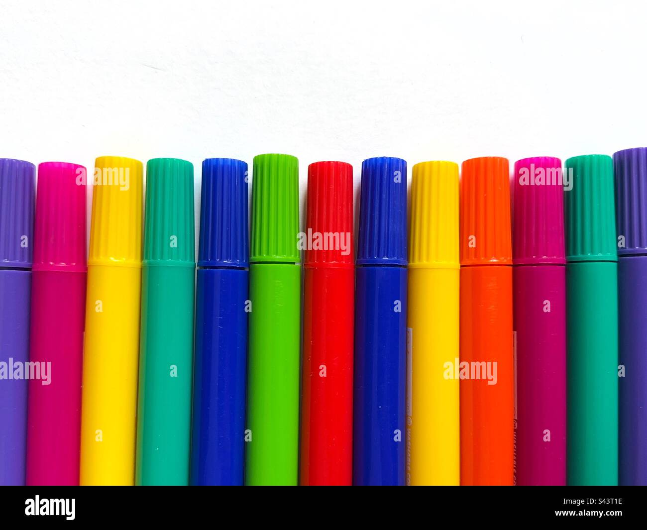 Row of coloured marker pens against a plain white background. Copy ...