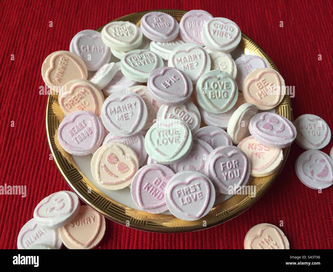 Love Hearts. Love Hearts in a white dish with a gold rim on a red ...