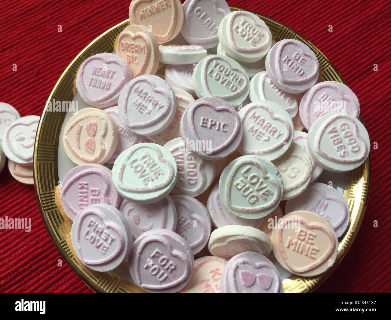 Love Hearts. Love Hearts in a white dish with a gold rim on a red ...