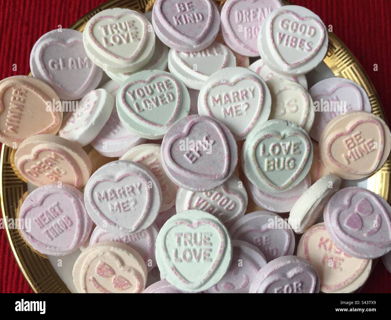 Love Hearts. Love Hearts in a white dish with a gold rim on a red ...