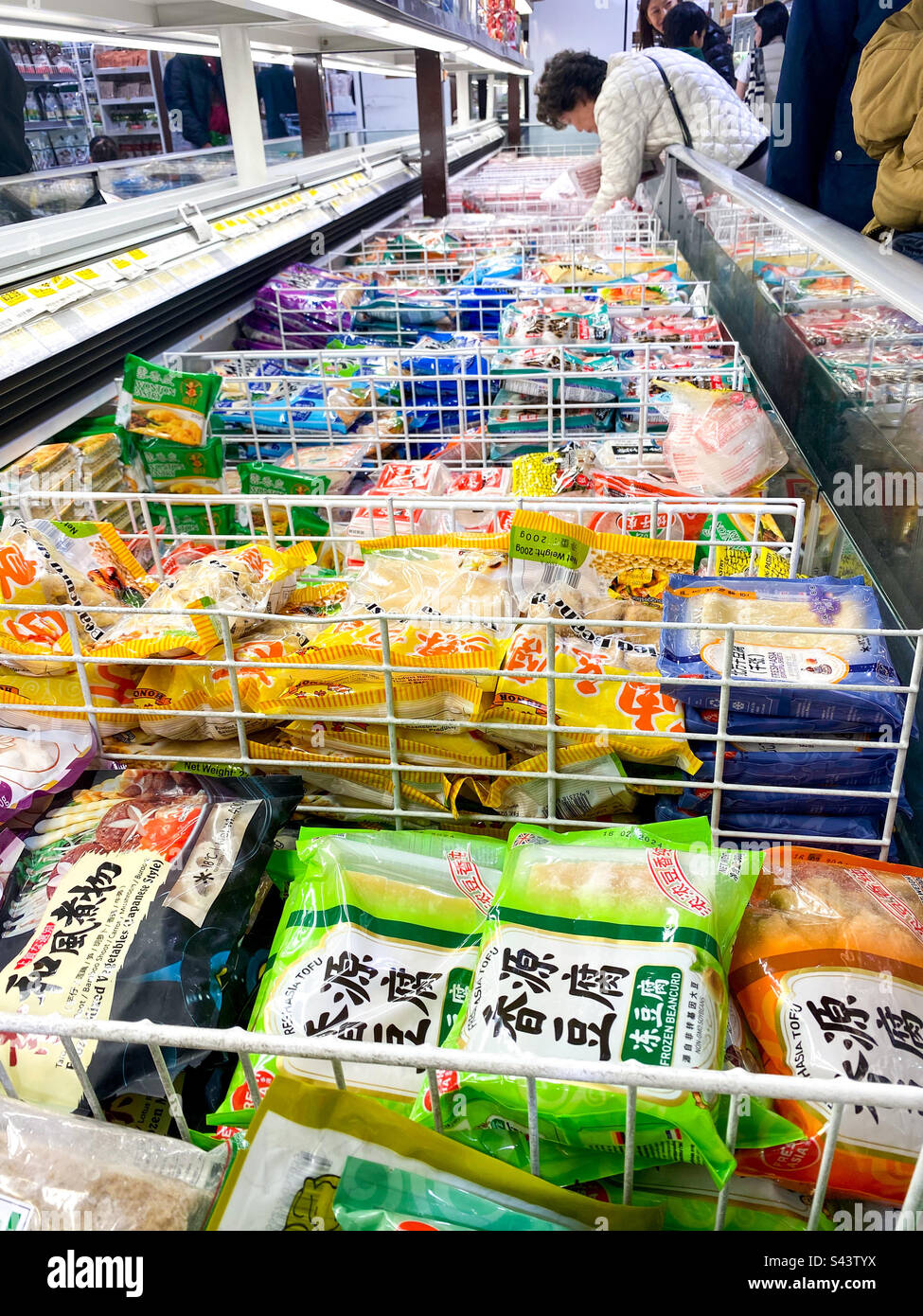 Products in the freezer section of an Asian supermarket. A lady reaches ...