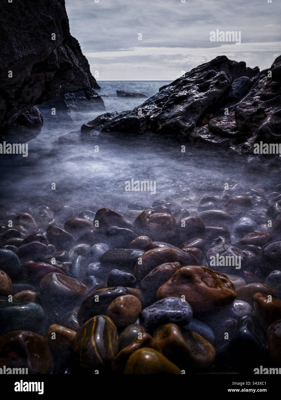 Long exposure of tide coming in over pebbles Stock Photo - Alamy