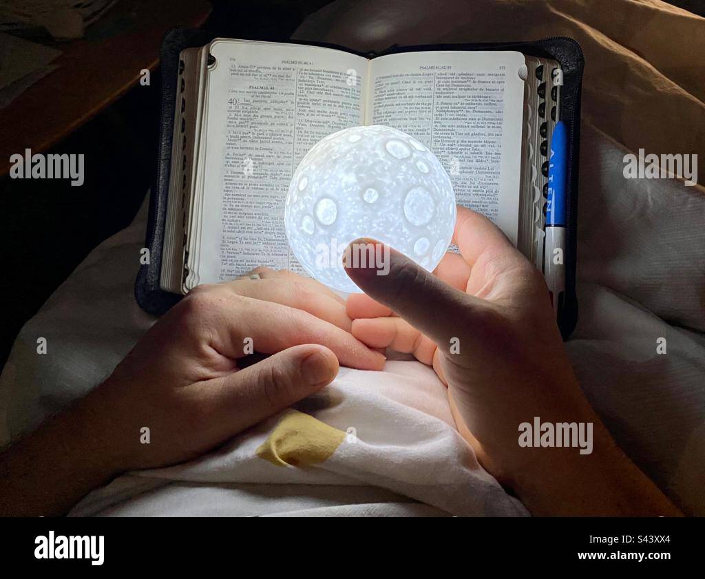 Staying in bed and reading the bible at the moon light holding it in my ...