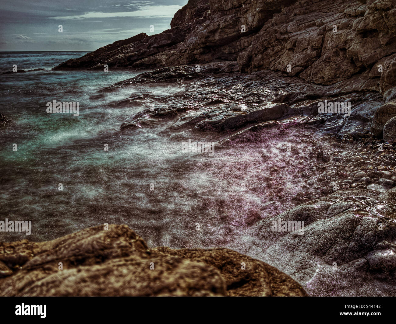 Tide coming in to cliff face on beach Stock Photo - Alamy
