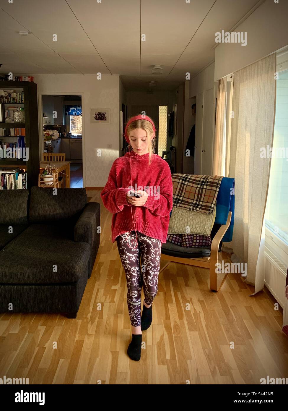 Young 11 year old teen teenager girl in pink headphones choosing tracks ...