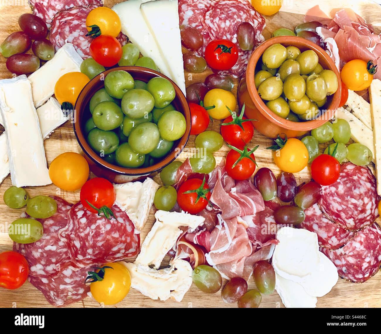 Charcuterie board with olives, hams, cheeses, tomatoes and grapes Stock ...