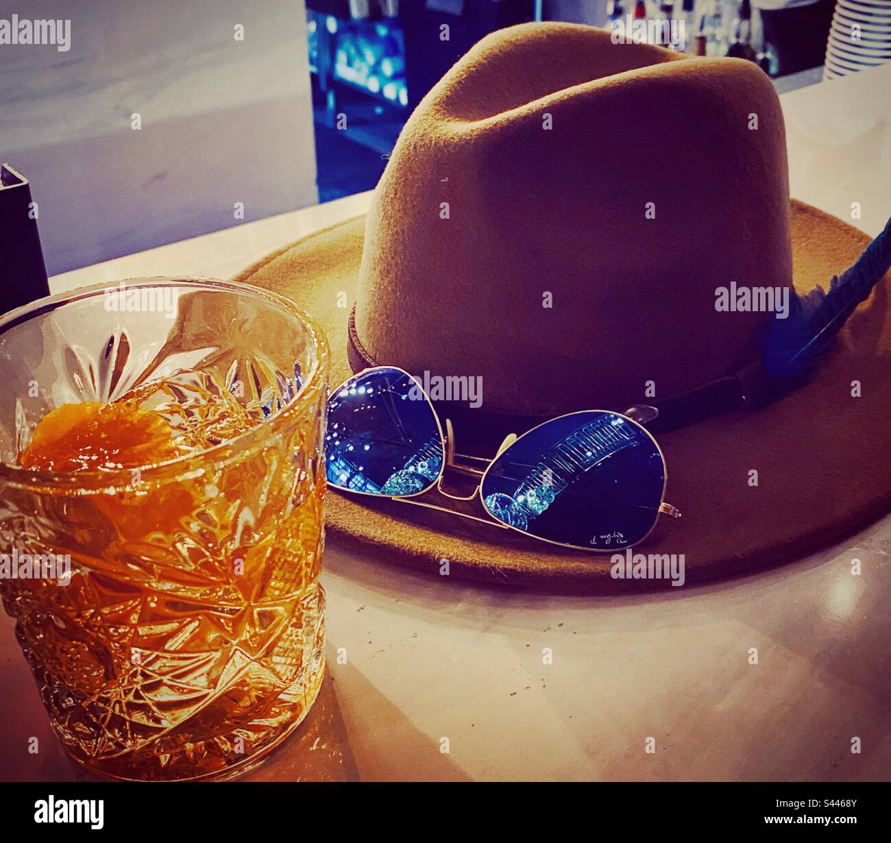 Cowboy hat with blue Ray Ban aviator sunglasses, on a bar counter, with ...