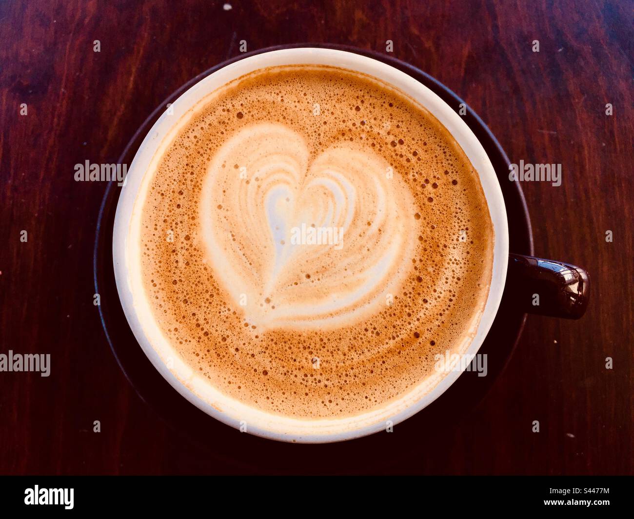 Perfect cuppa. A heart shape floats on the foamy surface of a cup of ...