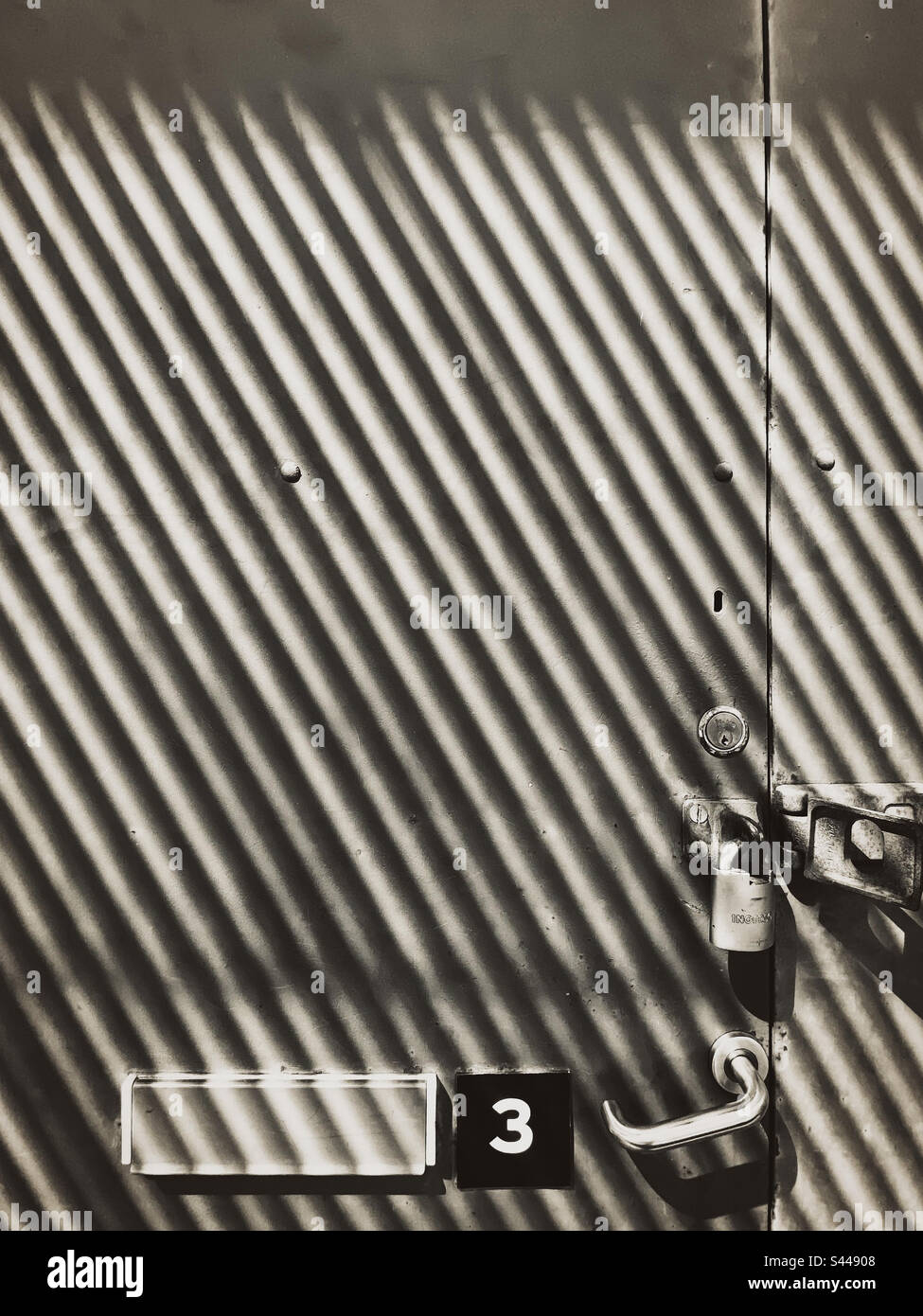 Striped shadows on a doorway at a unit at a warehouse in London Stock ...