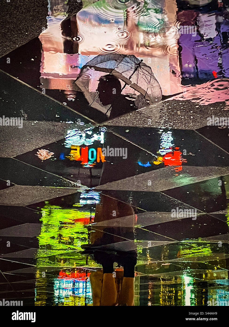 Reflection of a standing man holding an umbrella surrounded by colorful ...