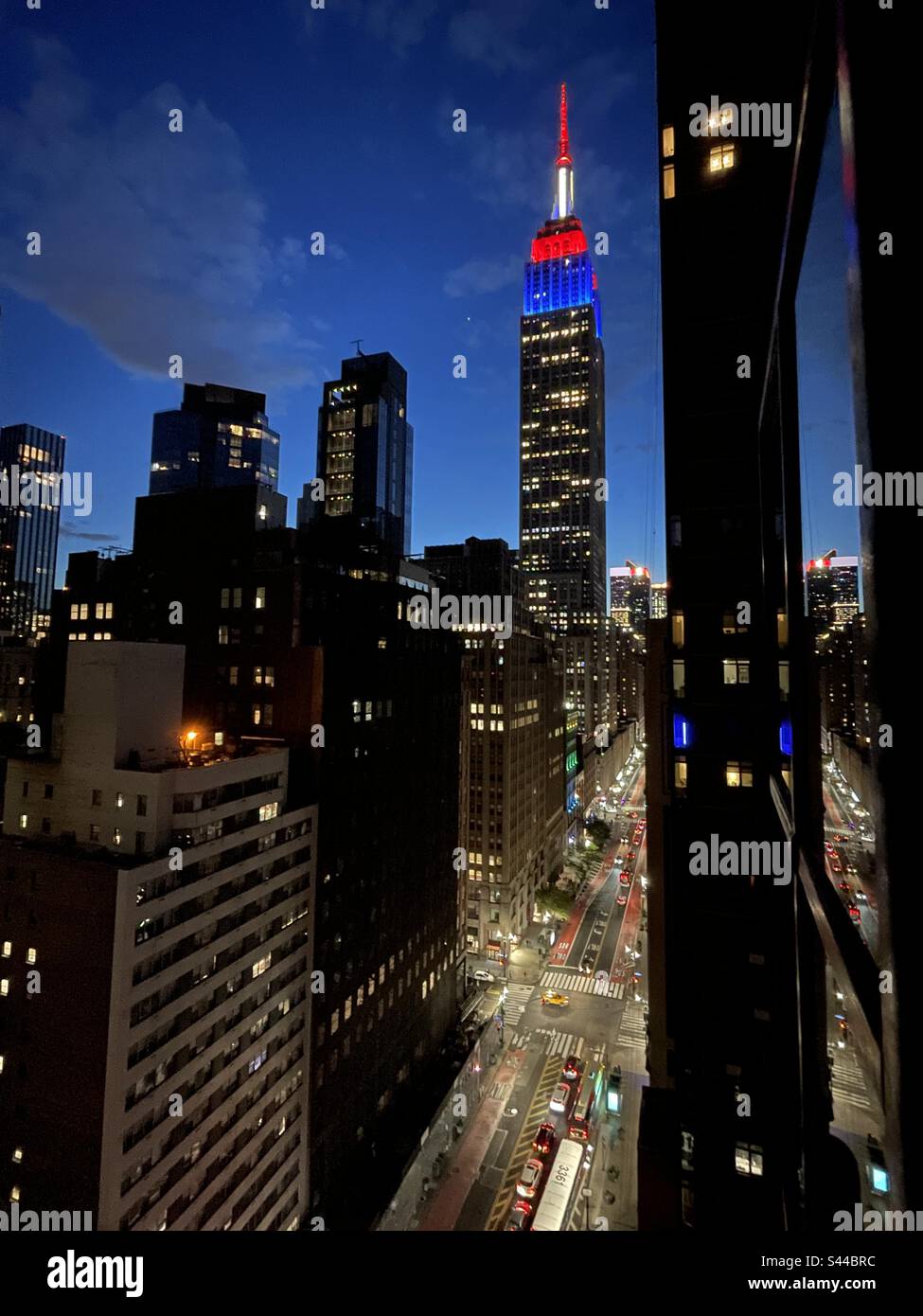 The empire state building brightly lit in red white and blue colors on ...