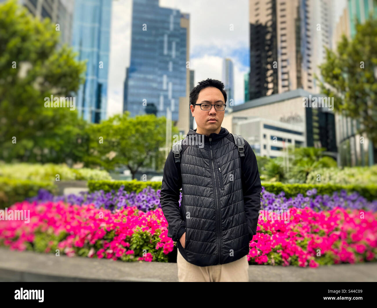 Springtime blooms in the city. Young Asian man standing in front of ...