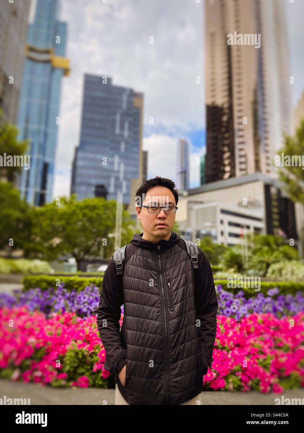 Springtime blooms in the city. Young Asian man standing in front of ...